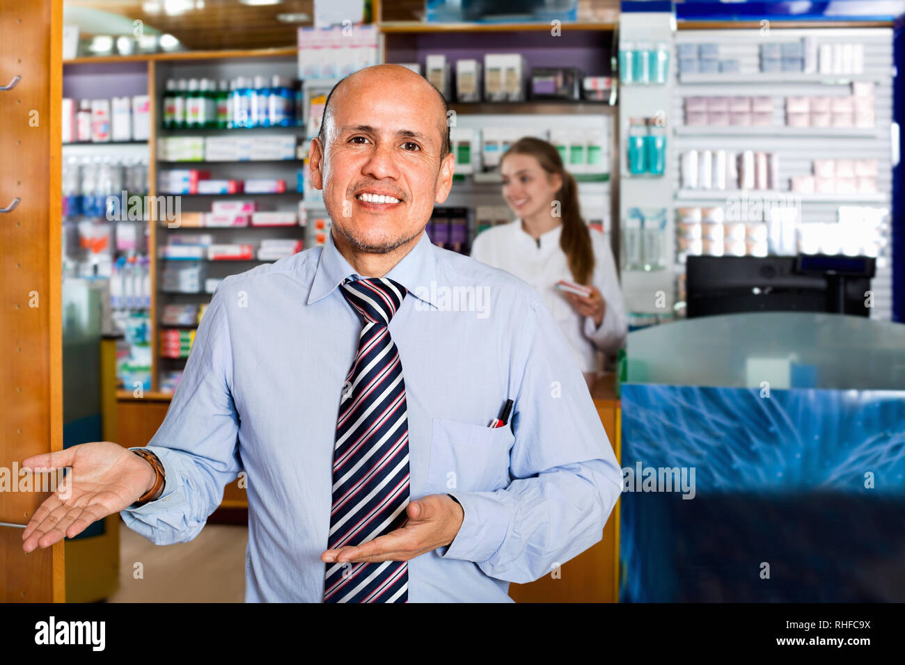 Smiling friendly pharmaceutists at reception of drugstore ready to help ...