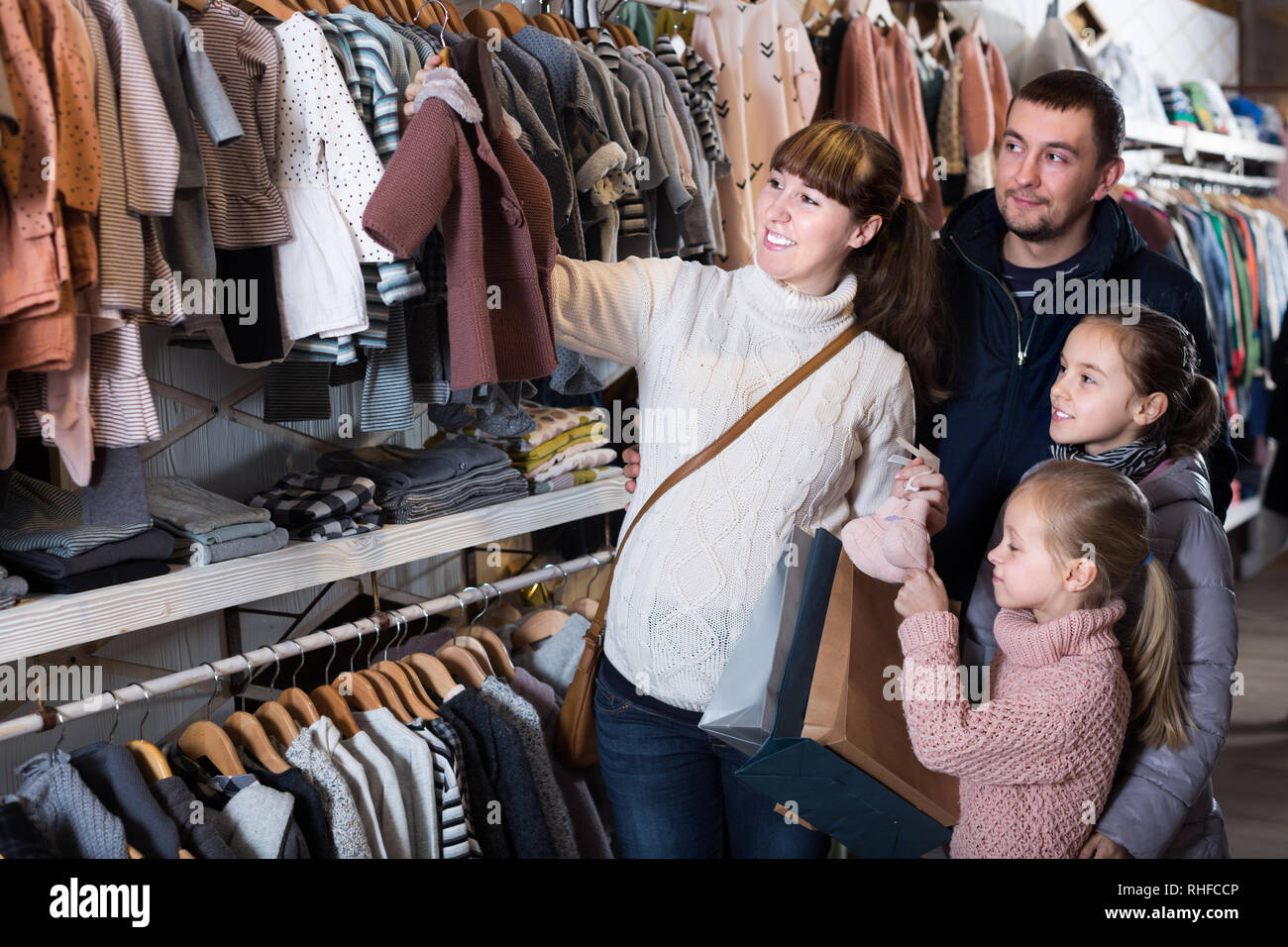 Young family with children choosing clothes for new baby in children’s ...