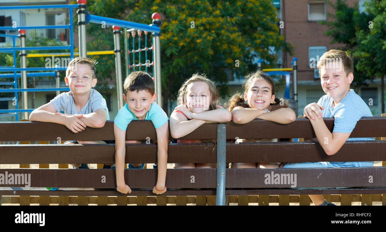 Five glad children sitting on a bench at the playground Stock Photo - Alamy