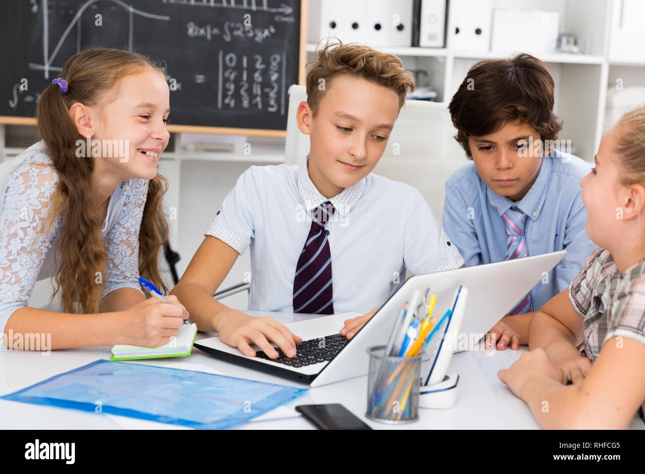 Group of children near laptop talking about mathematics indoors Stock ...