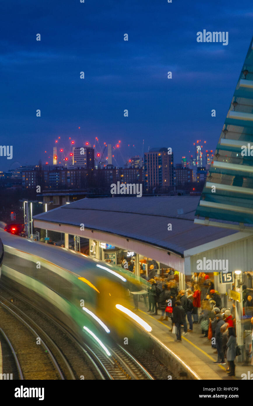 Trains at Clapham Junction station at dusk with Battersea Power Station ...