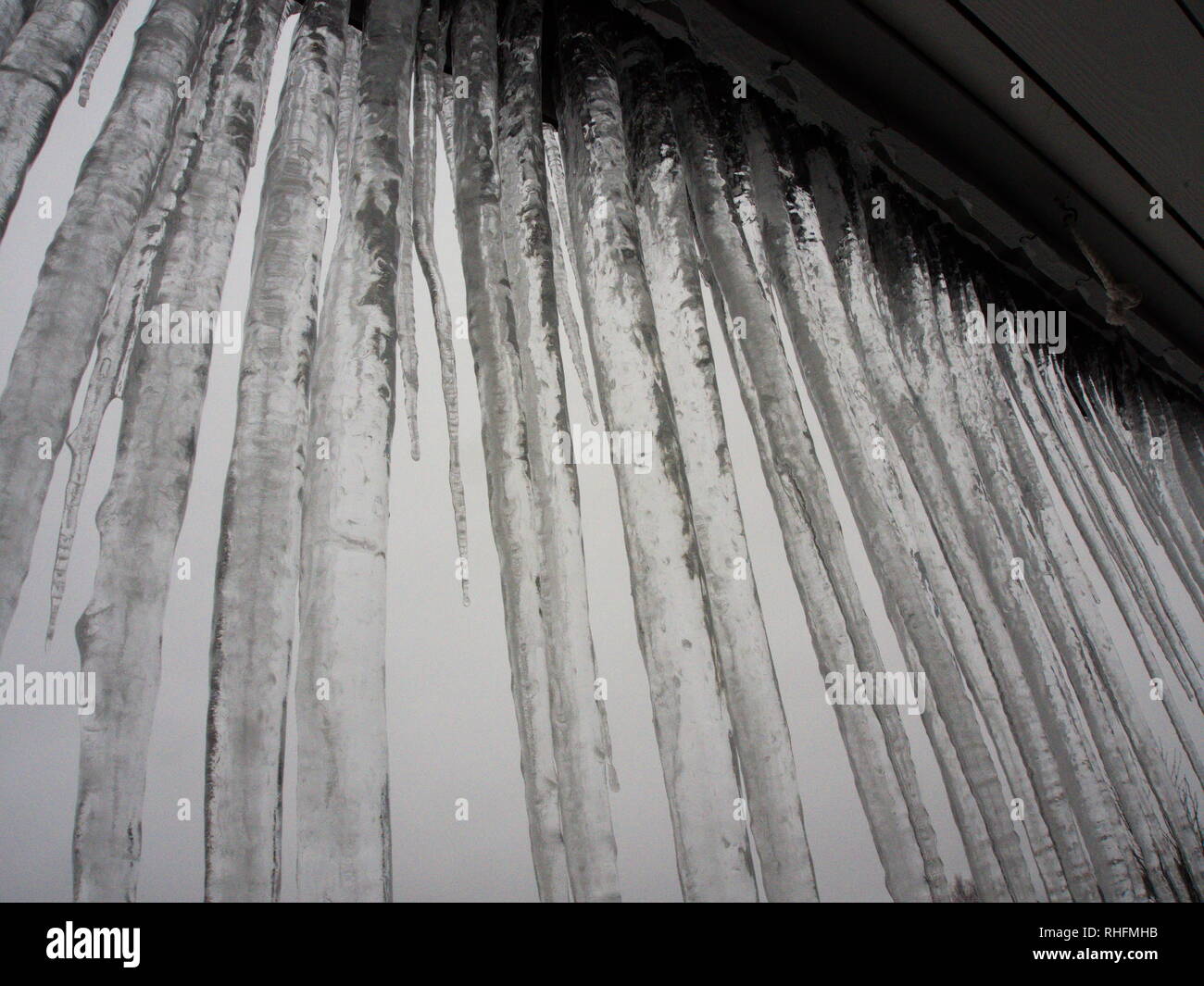 Icicles with a grey sky as background Stock Photo - Alamy