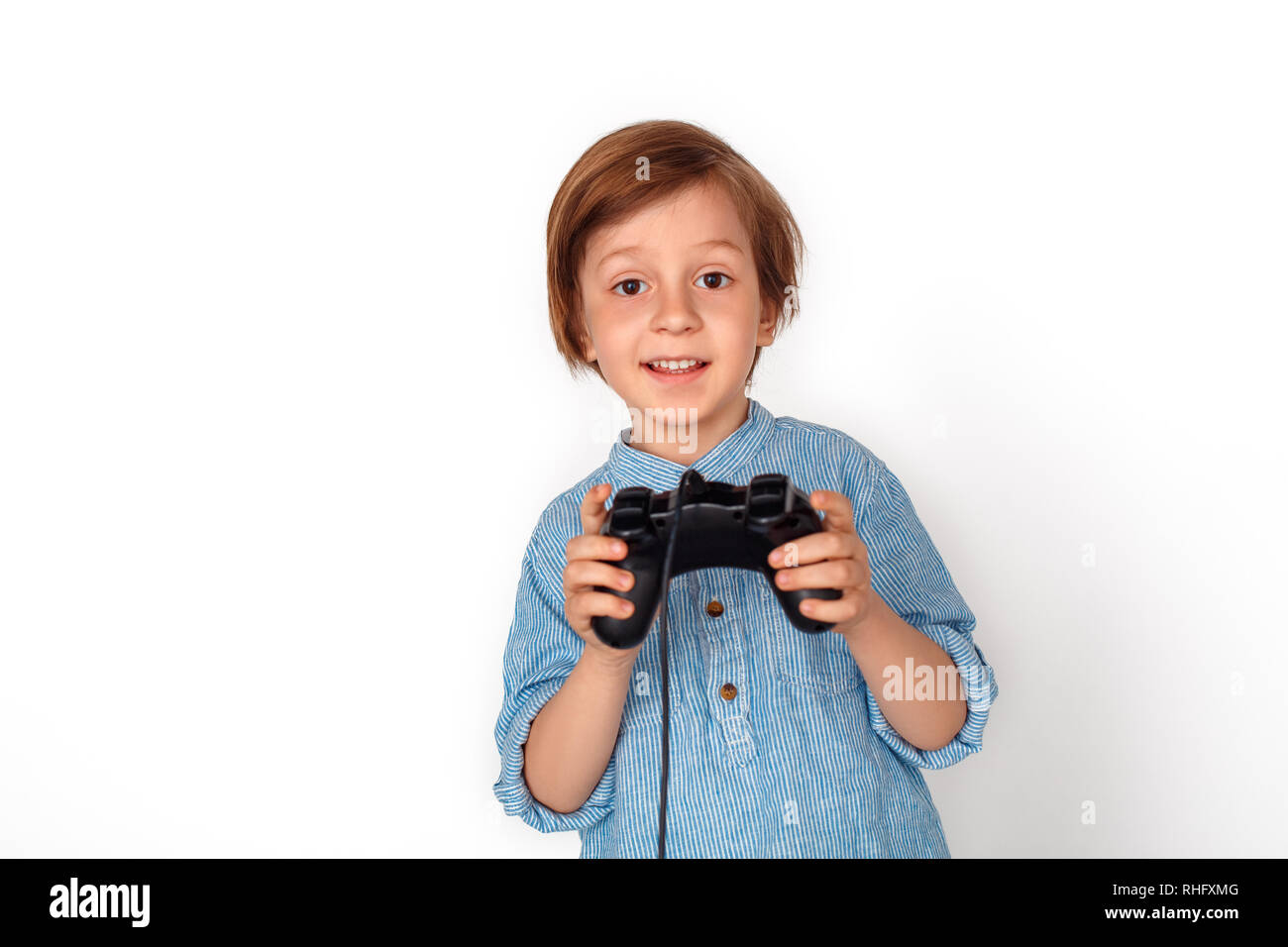 Little boy studio standing isolated on grey wall holding controller ...