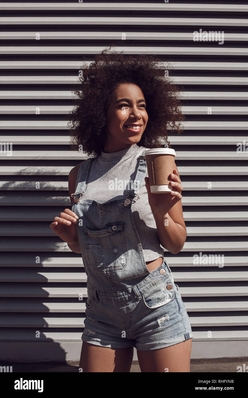 Young woman wearing denim overall shorts in the city street standing ...