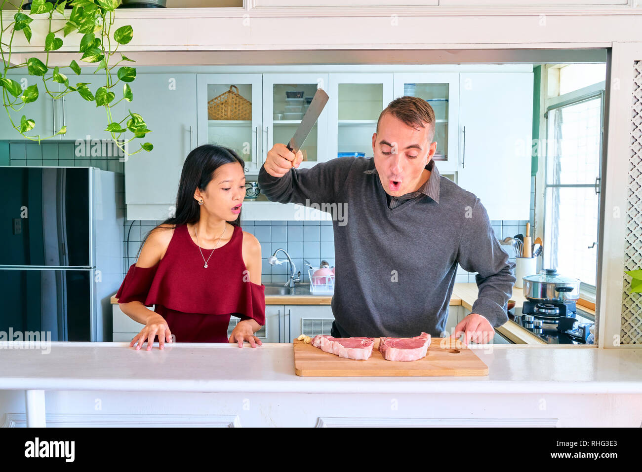 Lovely couple posing - man chop the meat and young woman watching Stock ...