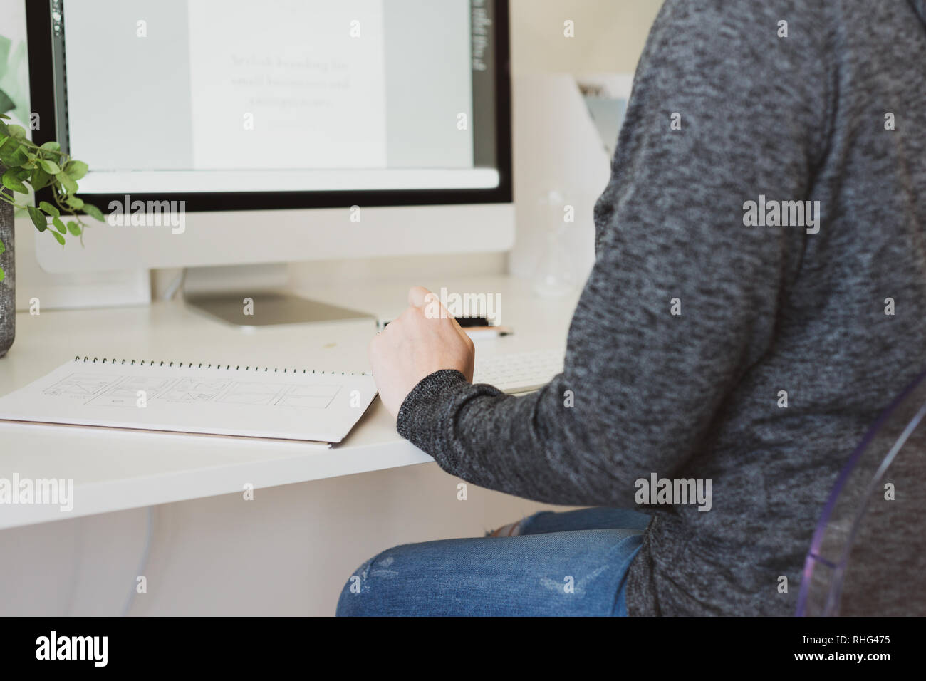 woman in home office, behind view of anonymous woman working at a desk ...