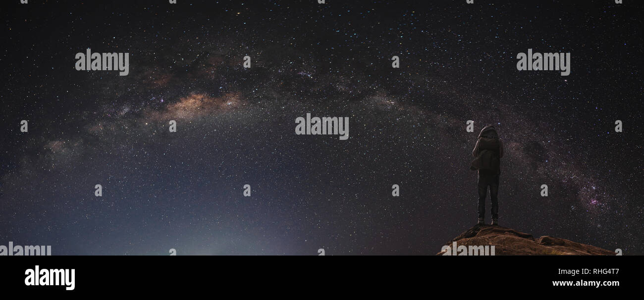 a man standing on the rock enjoying starry sky and milky way at night ...