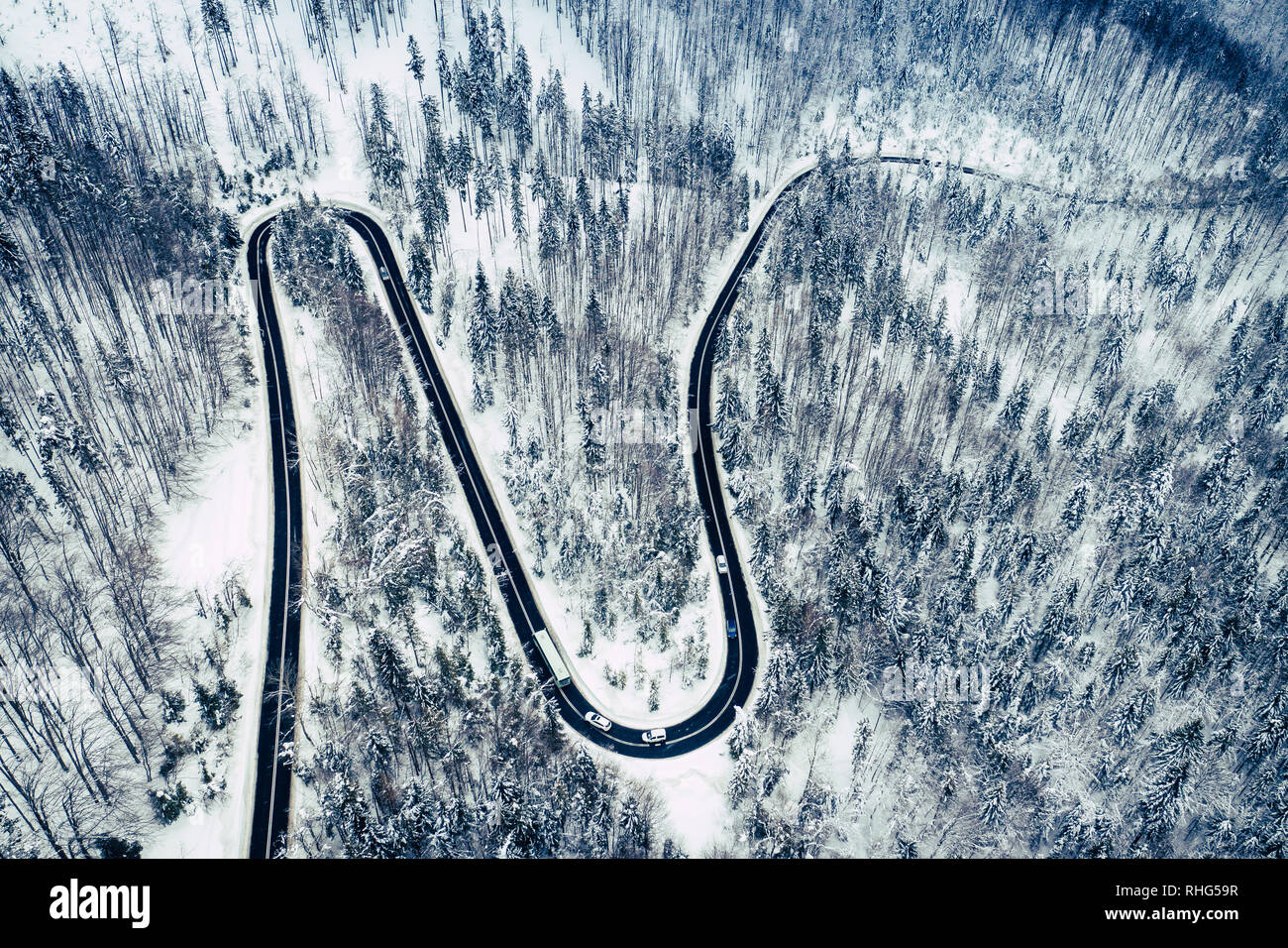Curvy windy road in snow covered forest, top down aerial view. Winter ...