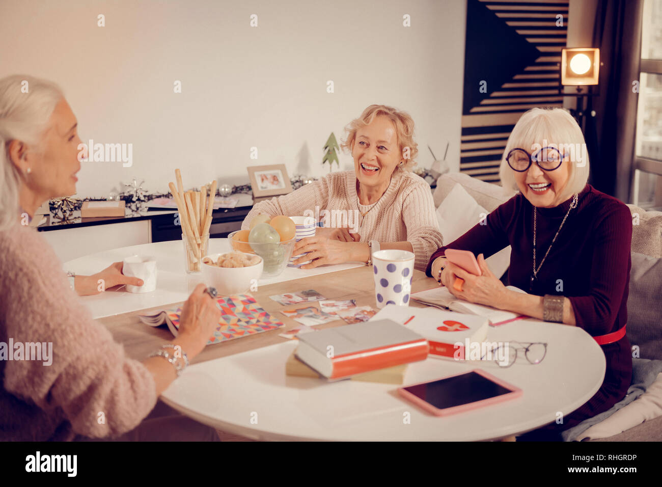 Positive senior women sitting around the table Stock Photo - Alamy