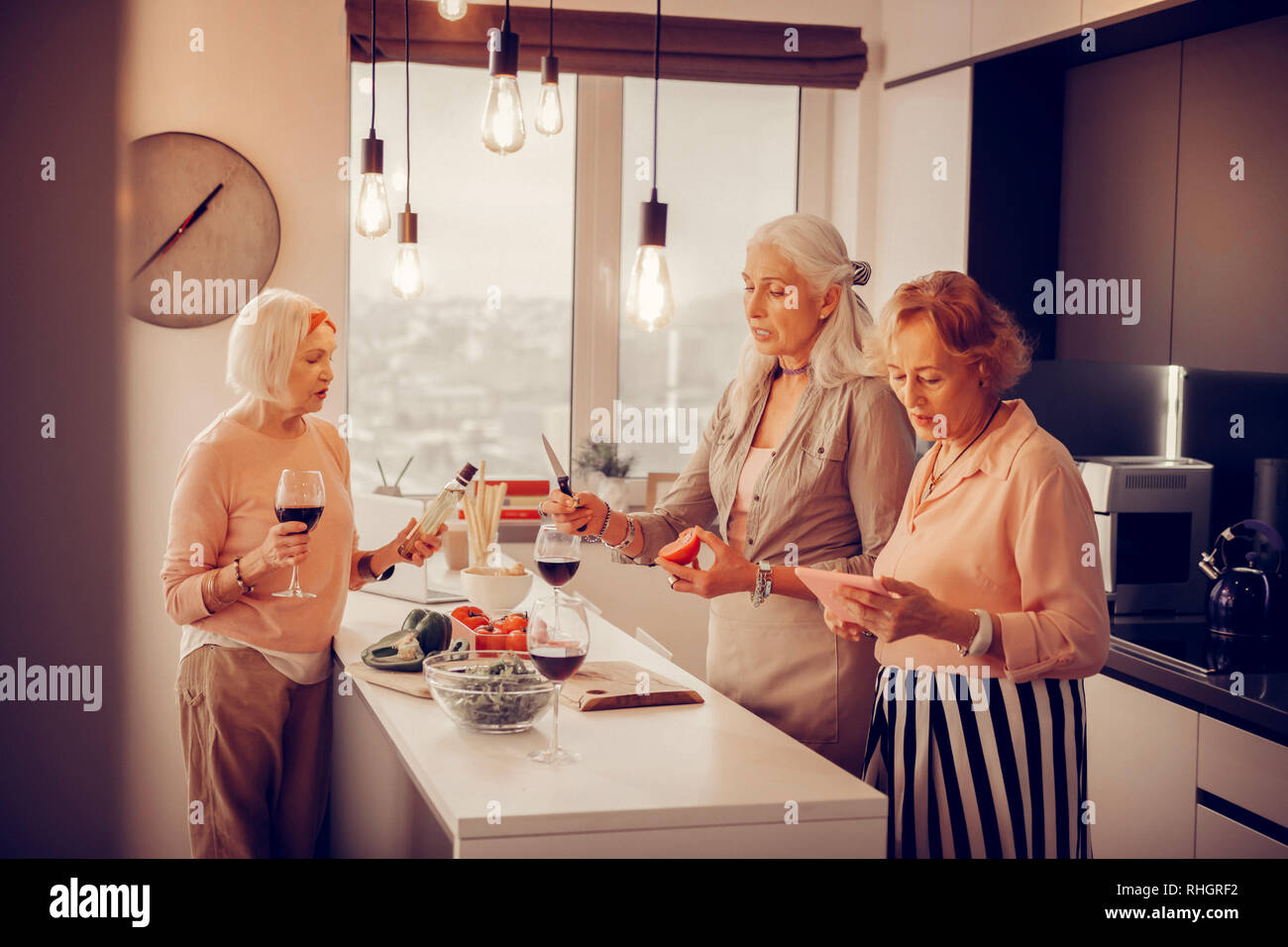 Pleasant good looking women cooking dinner together Stock Photo - Alamy