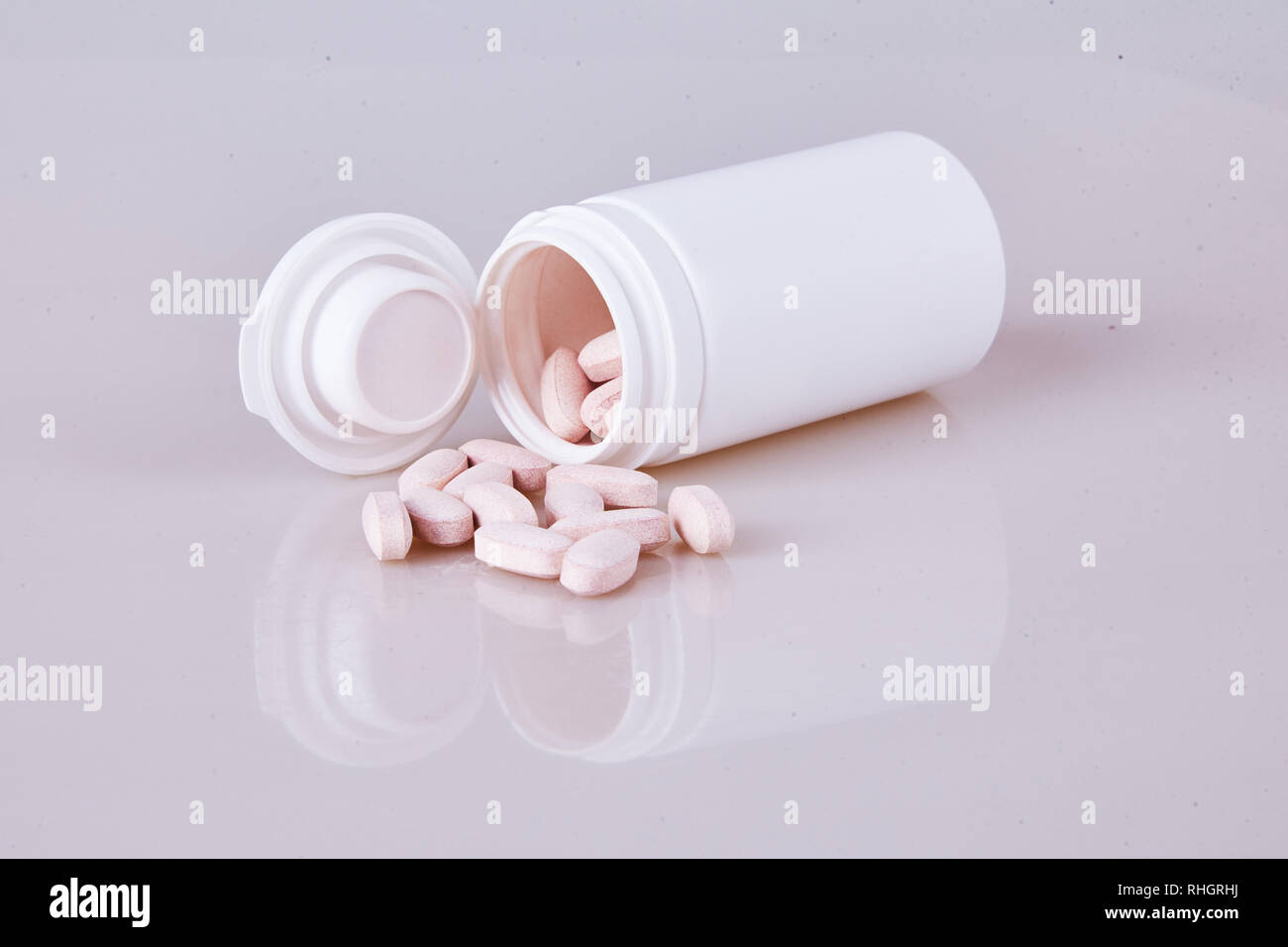 Vitamins (drugs) scattered and spilled out near an opened white plastic ...