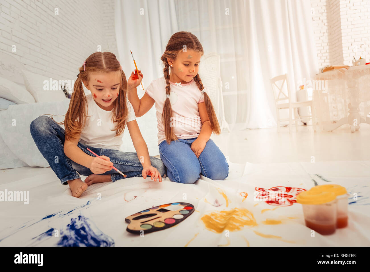 Positive nice girls painting together on the floor Stock Photo - Alamy