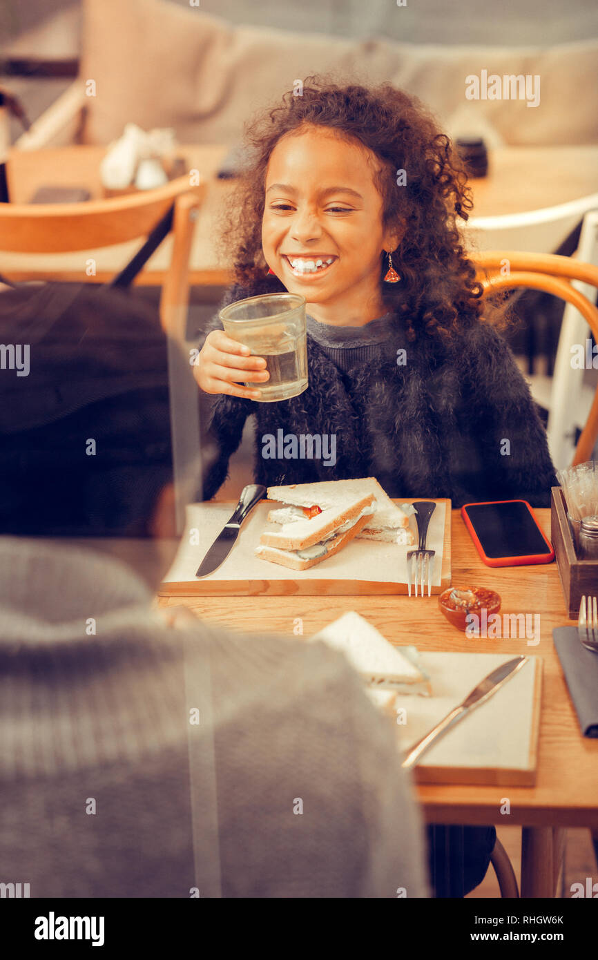 Girl laughing while drinking water in restaurant and speaking with ...