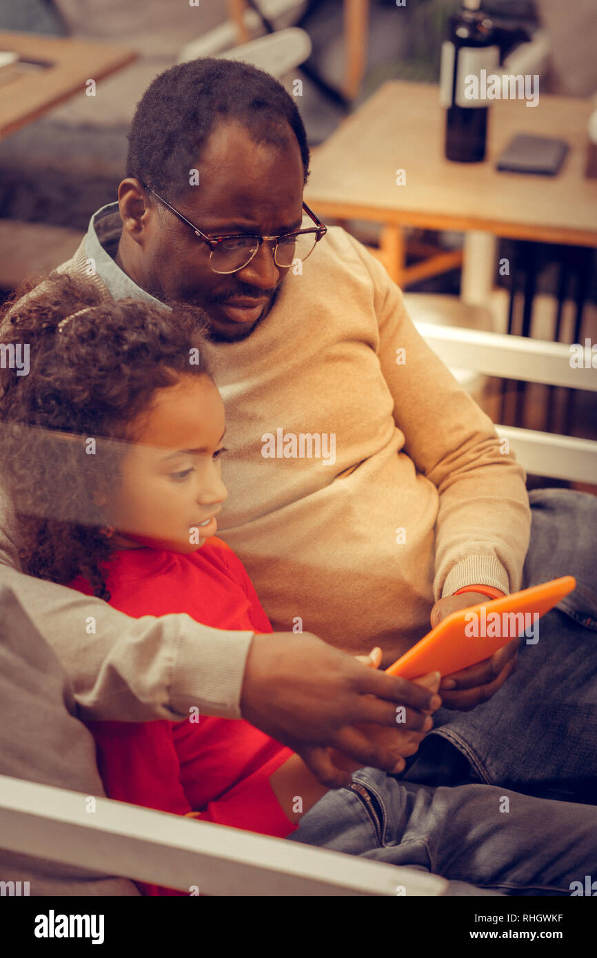 Father wearing glasses hugging his little princess watching cartoon ...