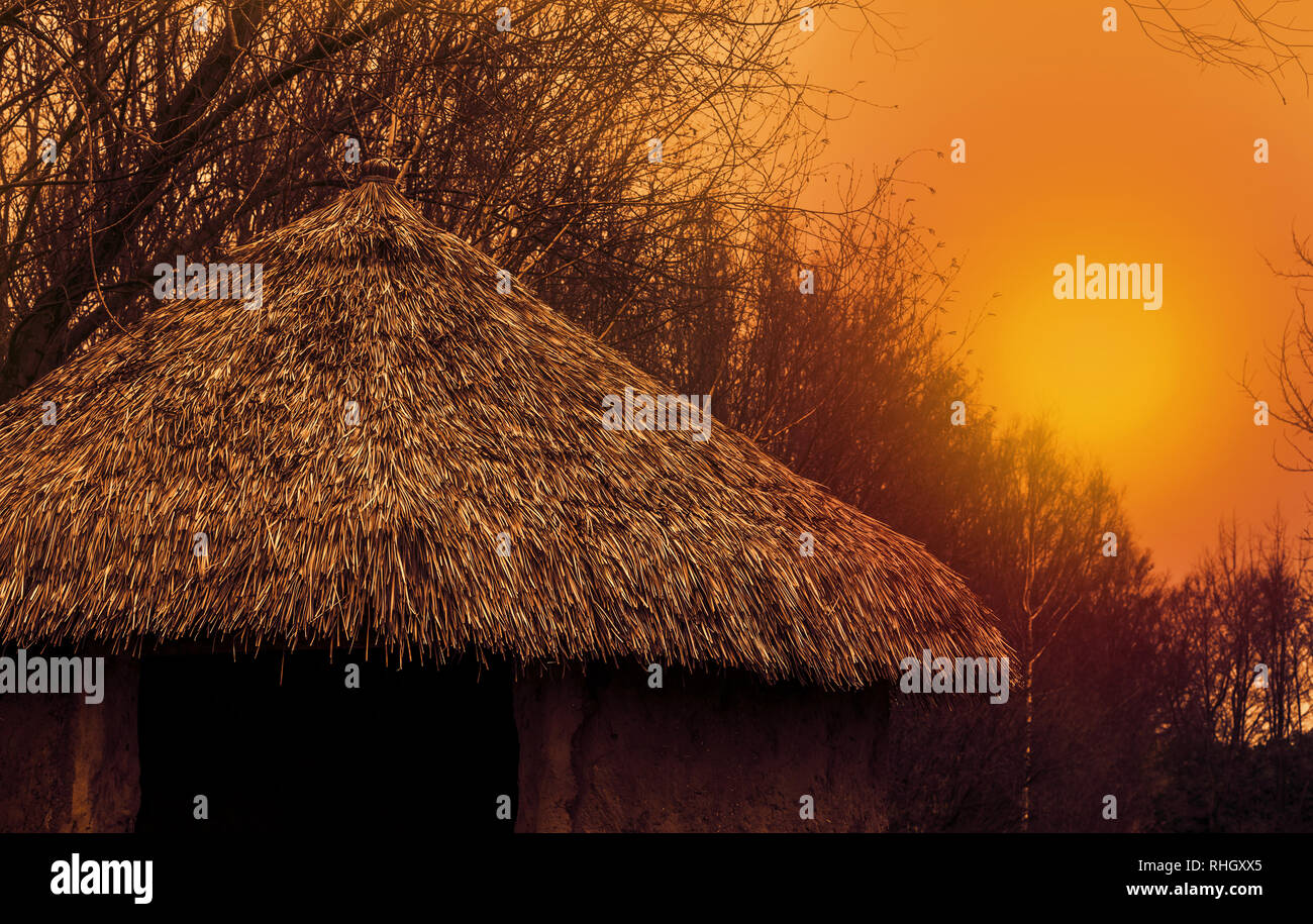 rooftop of a primitive home with a straw roof at sunset, nature scenery ...
