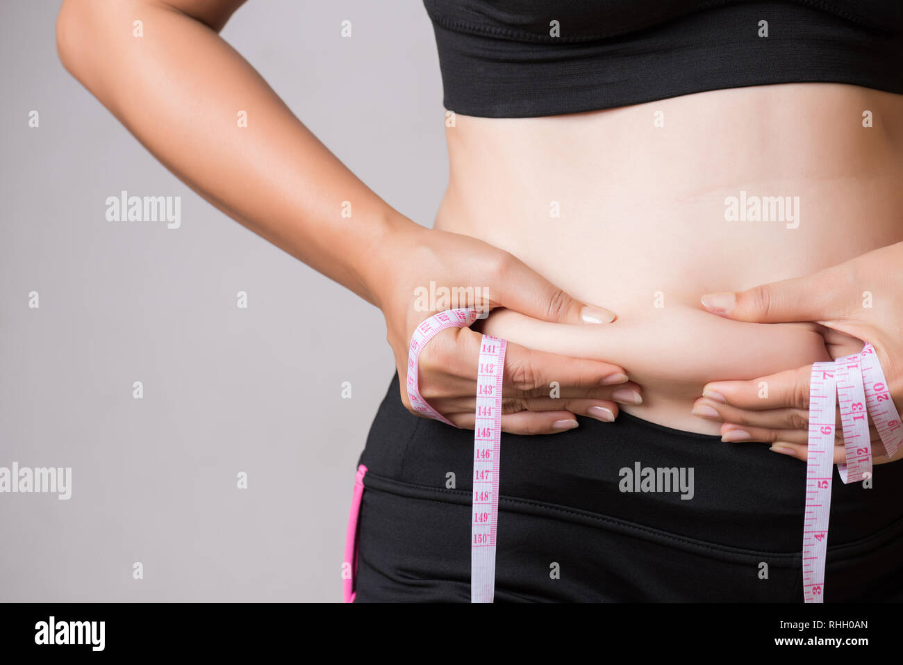 Fat woman hand holding excessive belly fat with measuring tape ...