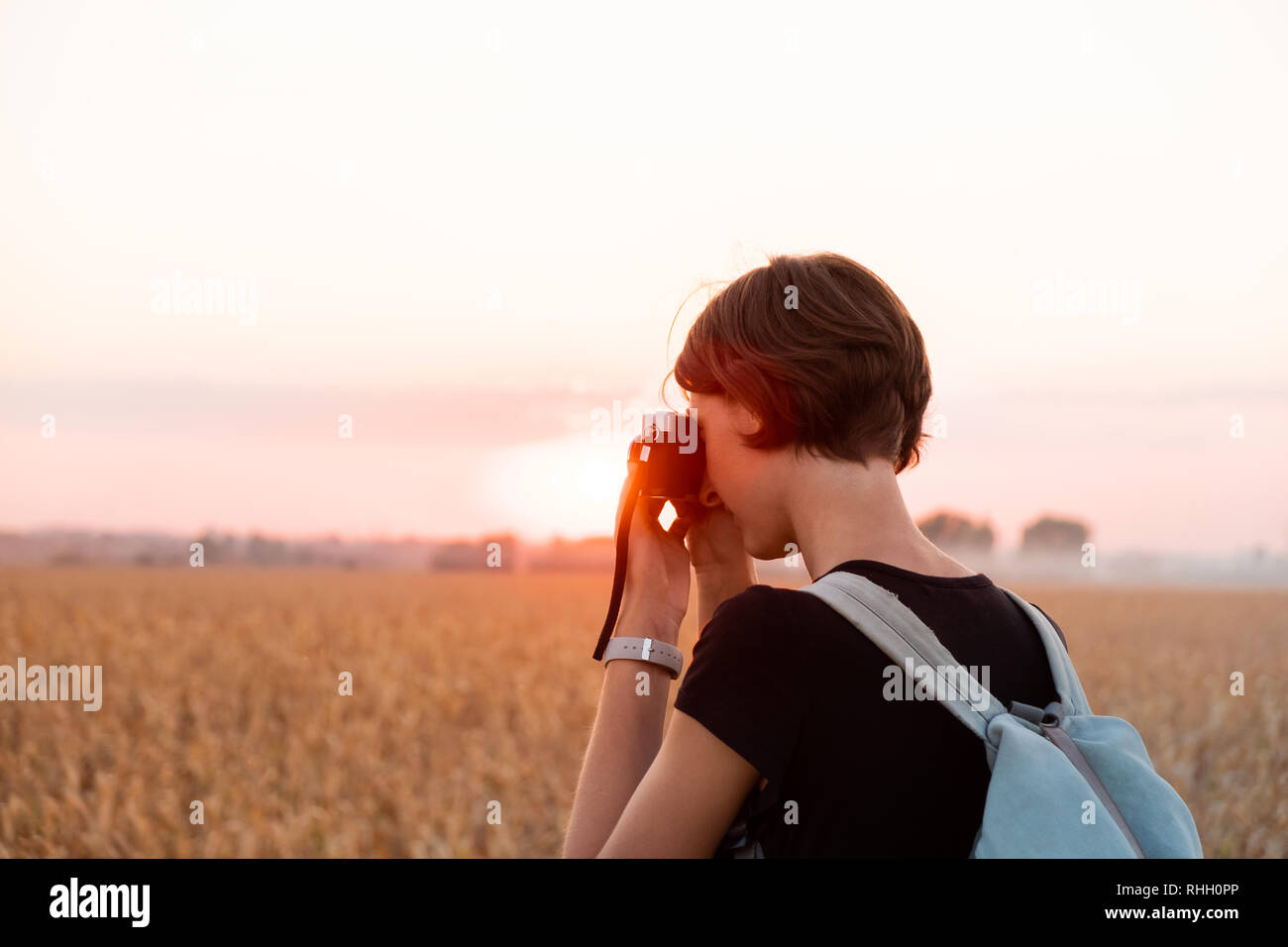 Backlit figure of a woman taking a photo in bright sunset. Female ...