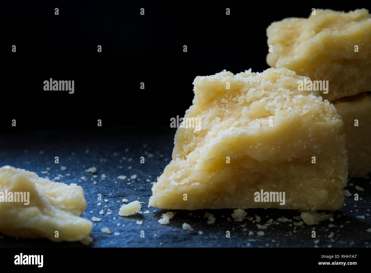 Moody images of parmesan cheese block on dark slate background with ...