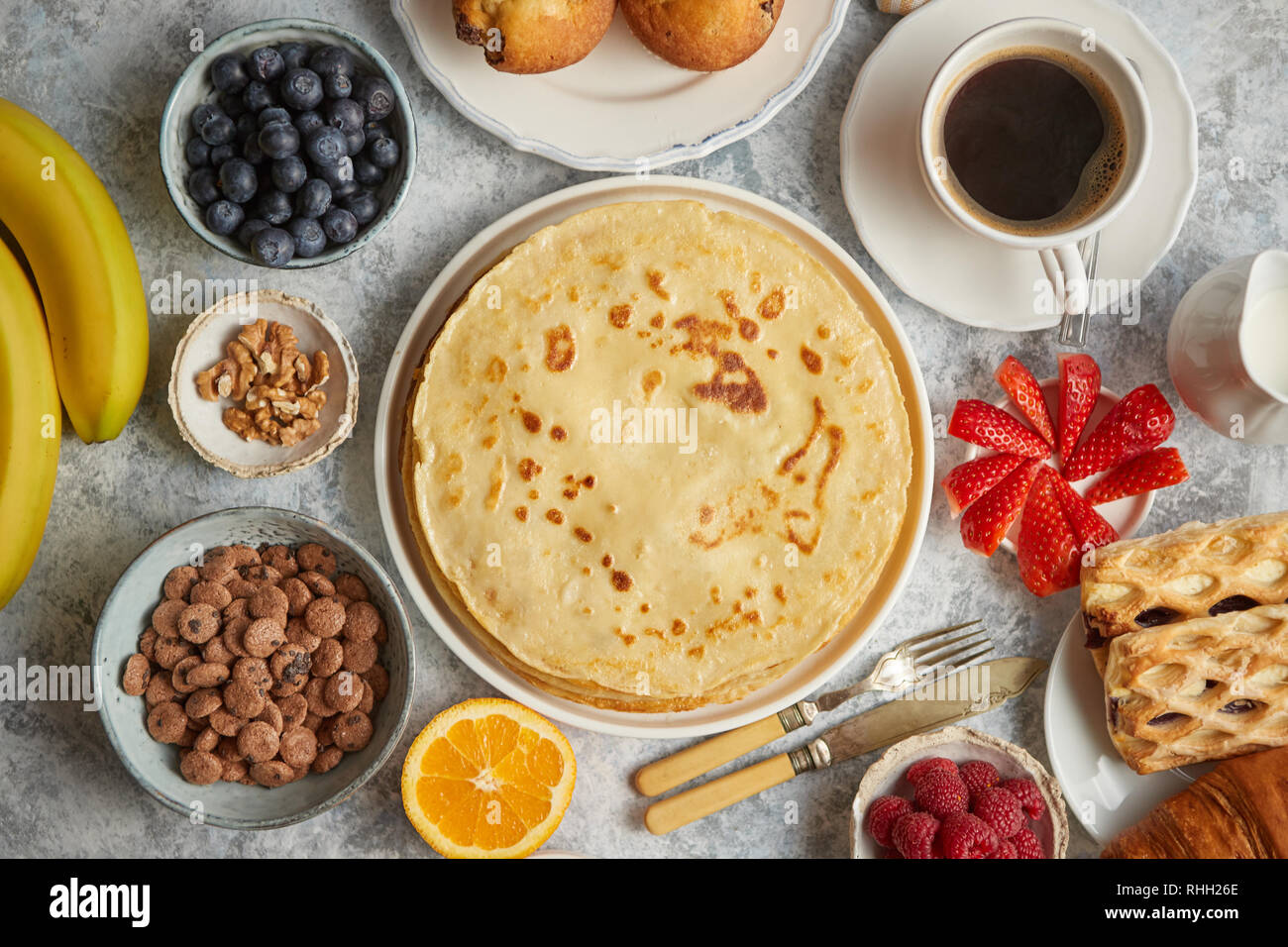 Breakfast table setting with fresh fruits, pancakes, coffee, croissants ...