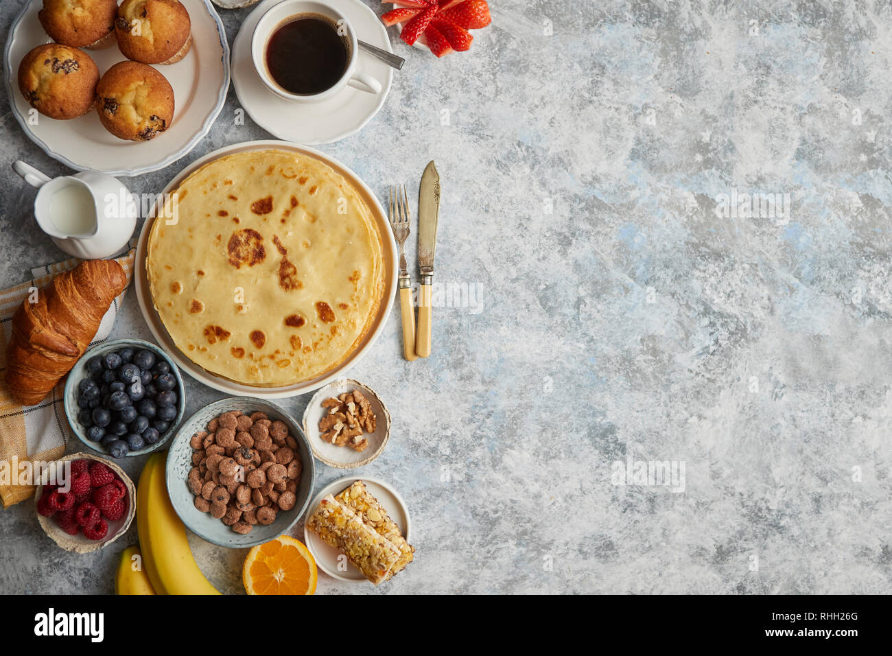 Breakfast table setting with fresh fruits, pancakes, coffee, croissants ...