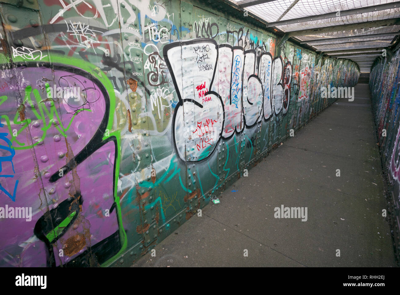 Multiple graffiti tags on wall of metal footbridge Stock Photo - Alamy