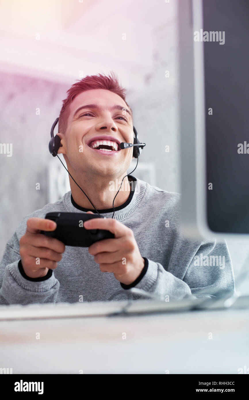 Handsome emotional student laughing after winning round in video game ...