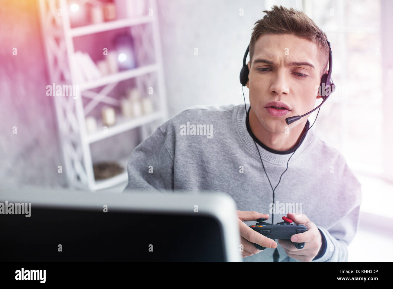 Blonde-haired student enjoying his weekend while playing computer games ...