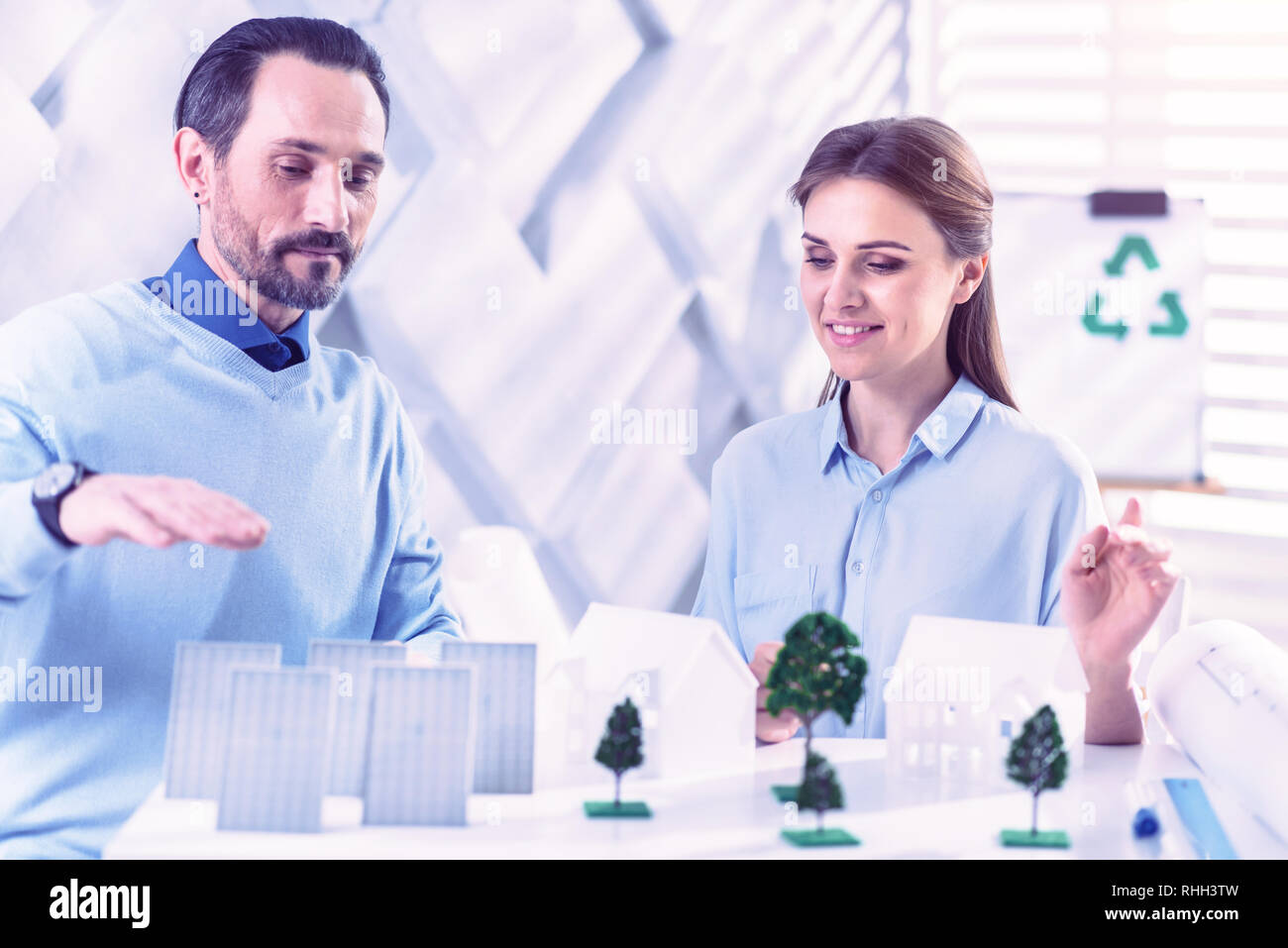 Calm engineer showing solar batteries while sitting with his colleague ...