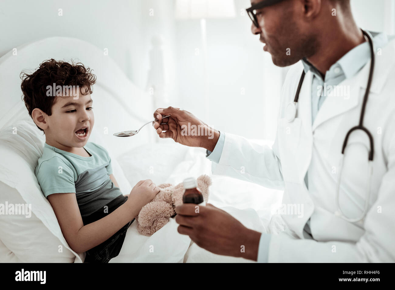 Professional dark-skinned doctor treating his young patient Stock Photo ...