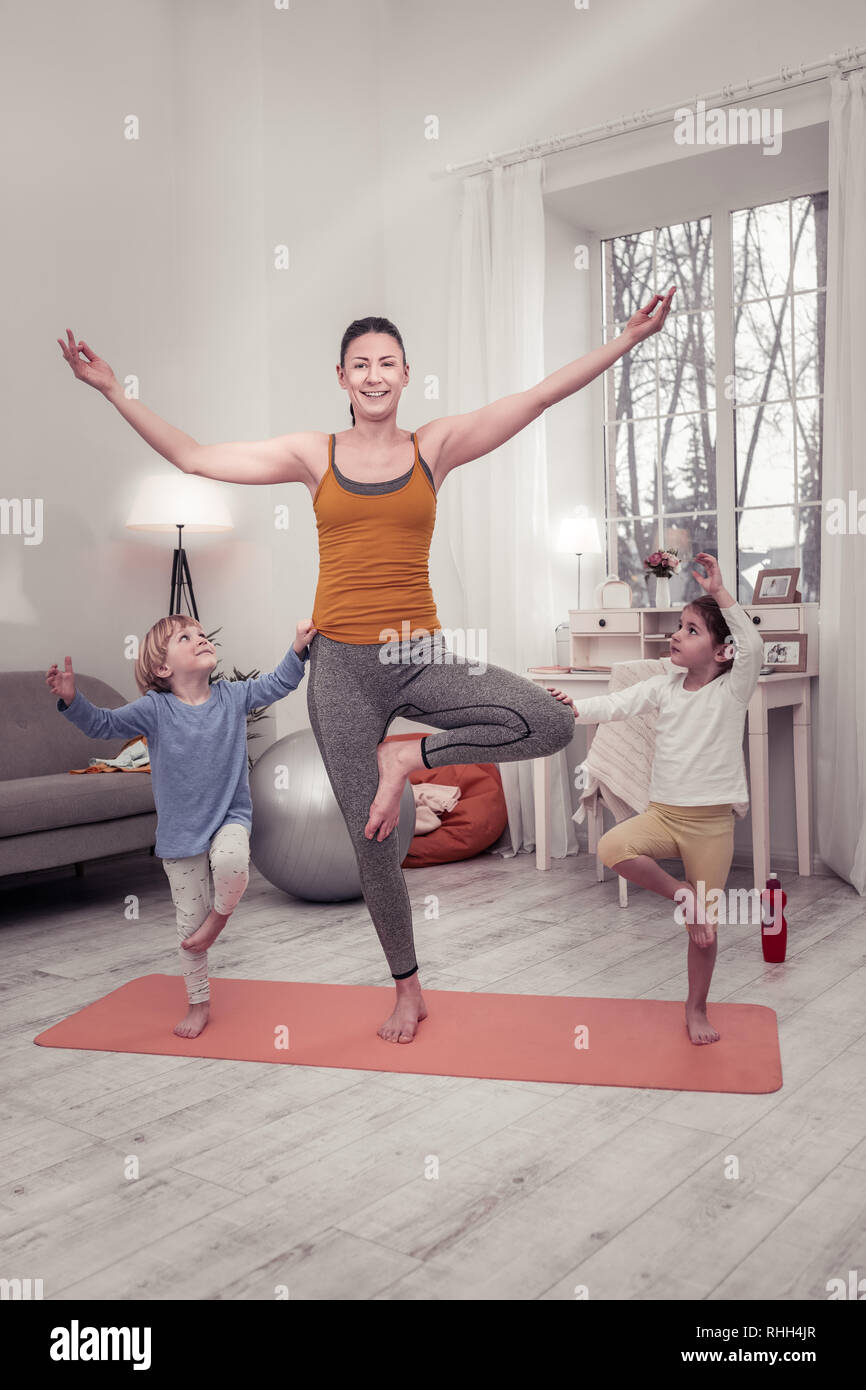 Mother teaching children keeping the balance in a yoga position Stock ...