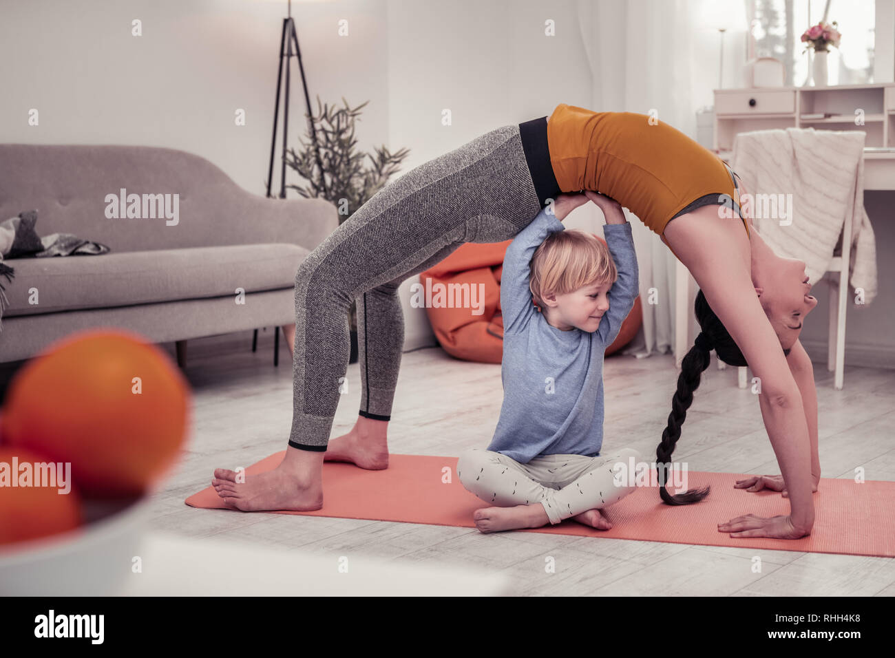 Kid supporting his mother doing a backbend Stock Photo - Alamy