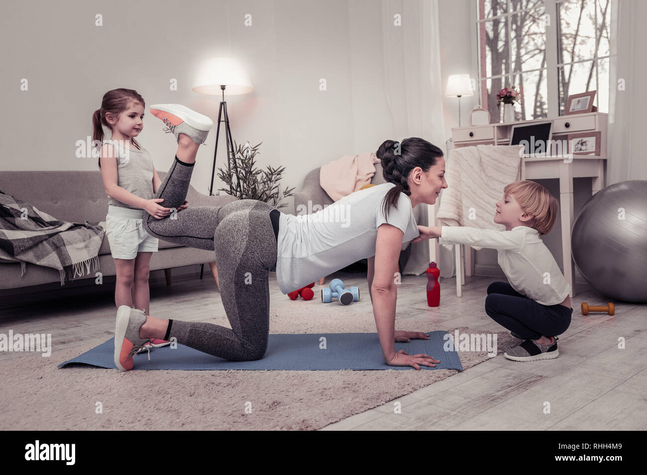 Woman doing sports at home feels disturbed by her children Stock Photo ...
