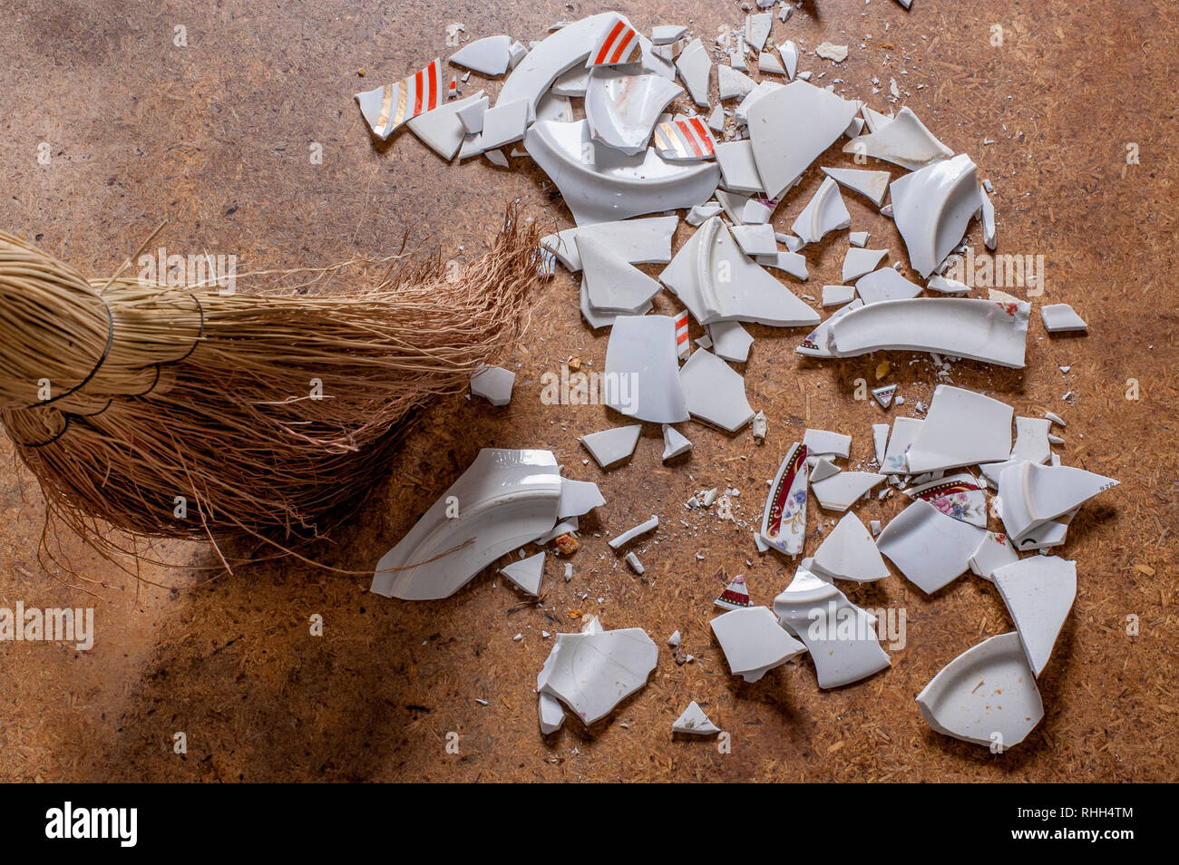 Straw broom sweeping pieces of shattered dishes. Splinters and ...