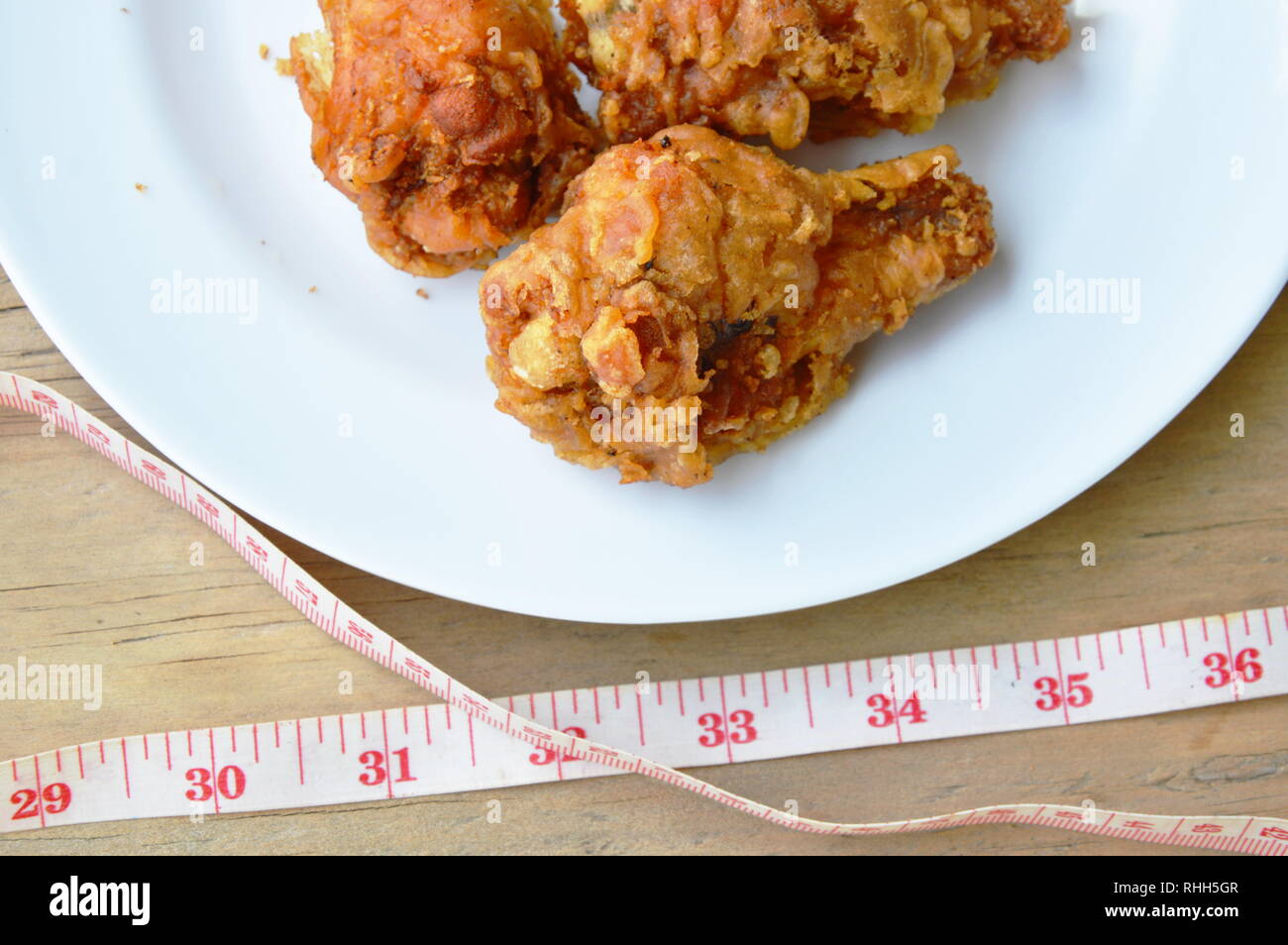 fried chicken leg and measuring tape for check waistline after eat ...