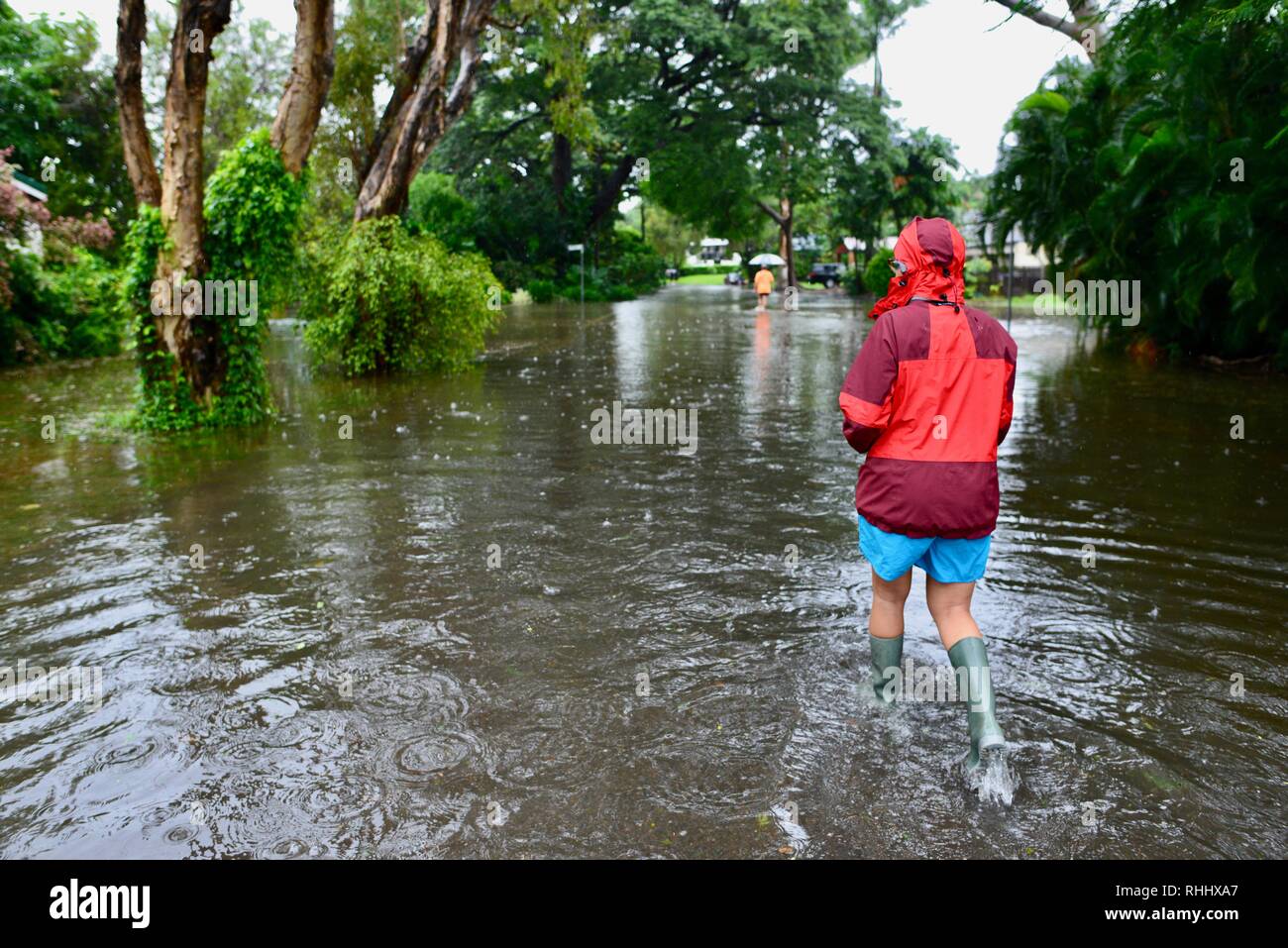 A woman in a red rain jacket wades through flood waters. Flooding ...