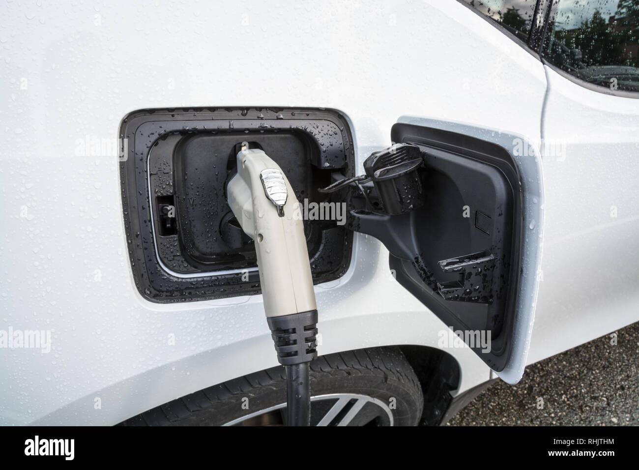 Electric vehicle with the power plug connected to the car Stock Photo ...