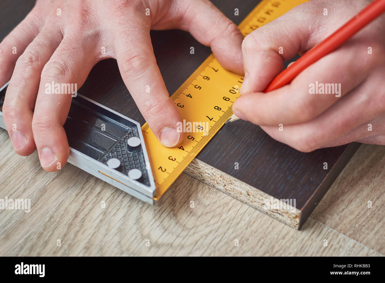 Male hands with ruler and pencil taking measurement of wooden plank ...