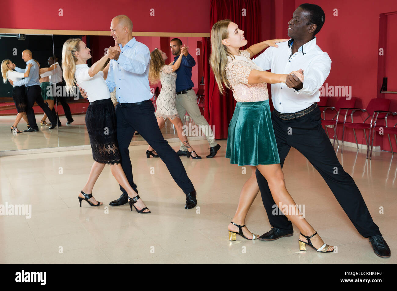 Young positive people dancing together slow ballroom dances in pairs ...