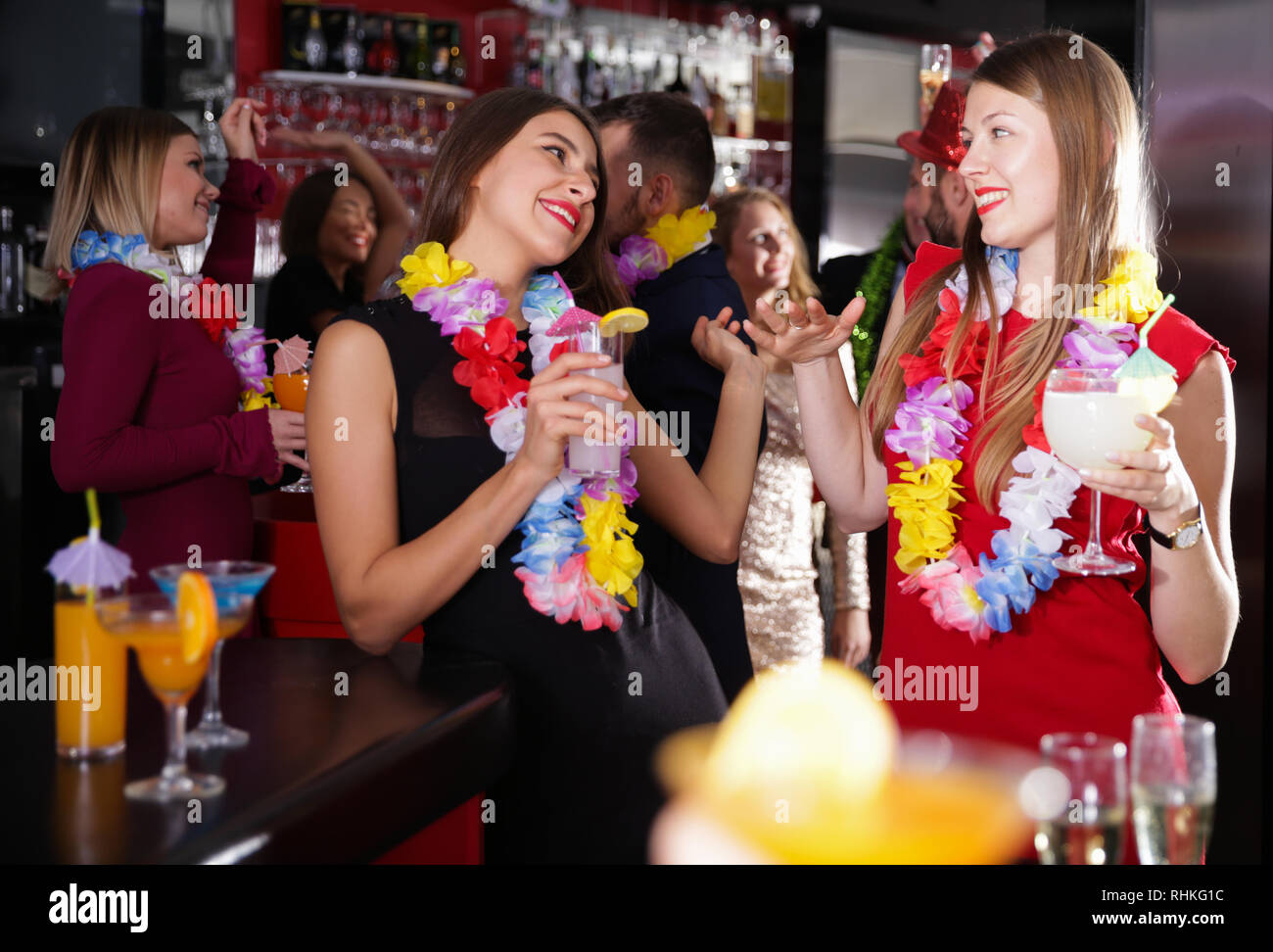 Two young women with cocktails having fun on Hawaiian party at ...