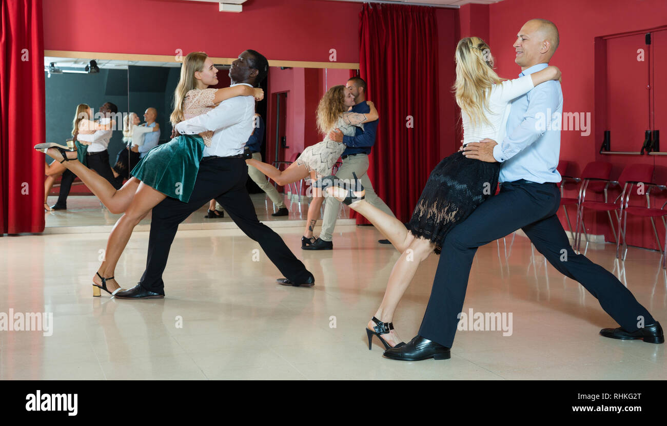 Portrait of positive adult pairs enjoying dancing in modern dance ...