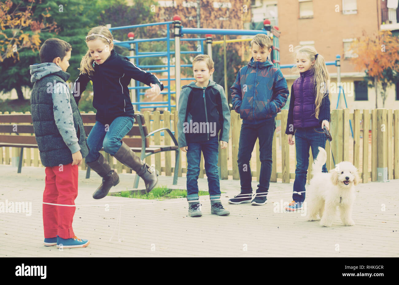 Smiling children skipping on chinese jumping elastic rope in yard Stock ...