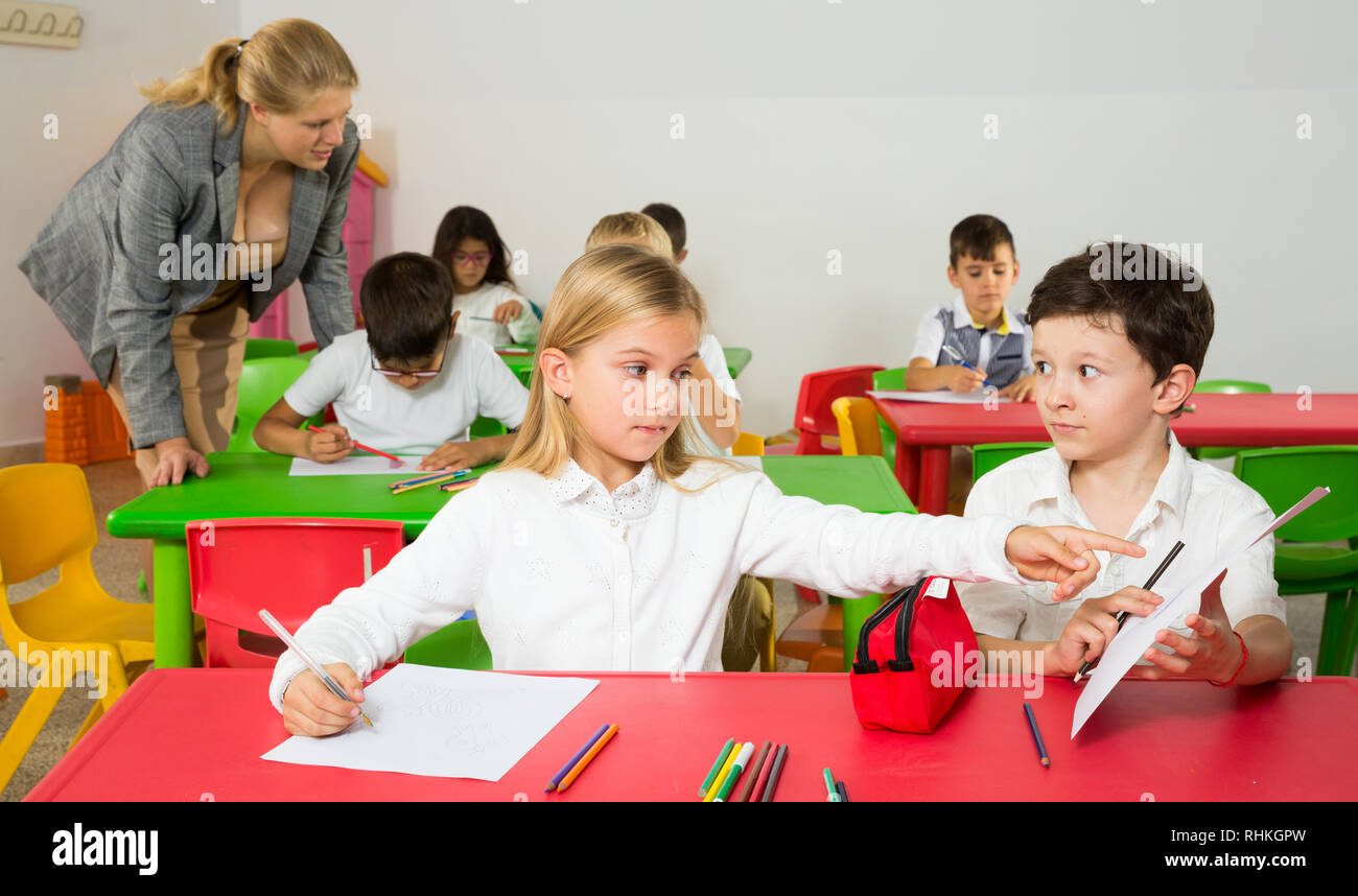 Portrait of children discussing theirs drawings during lesson in school ...