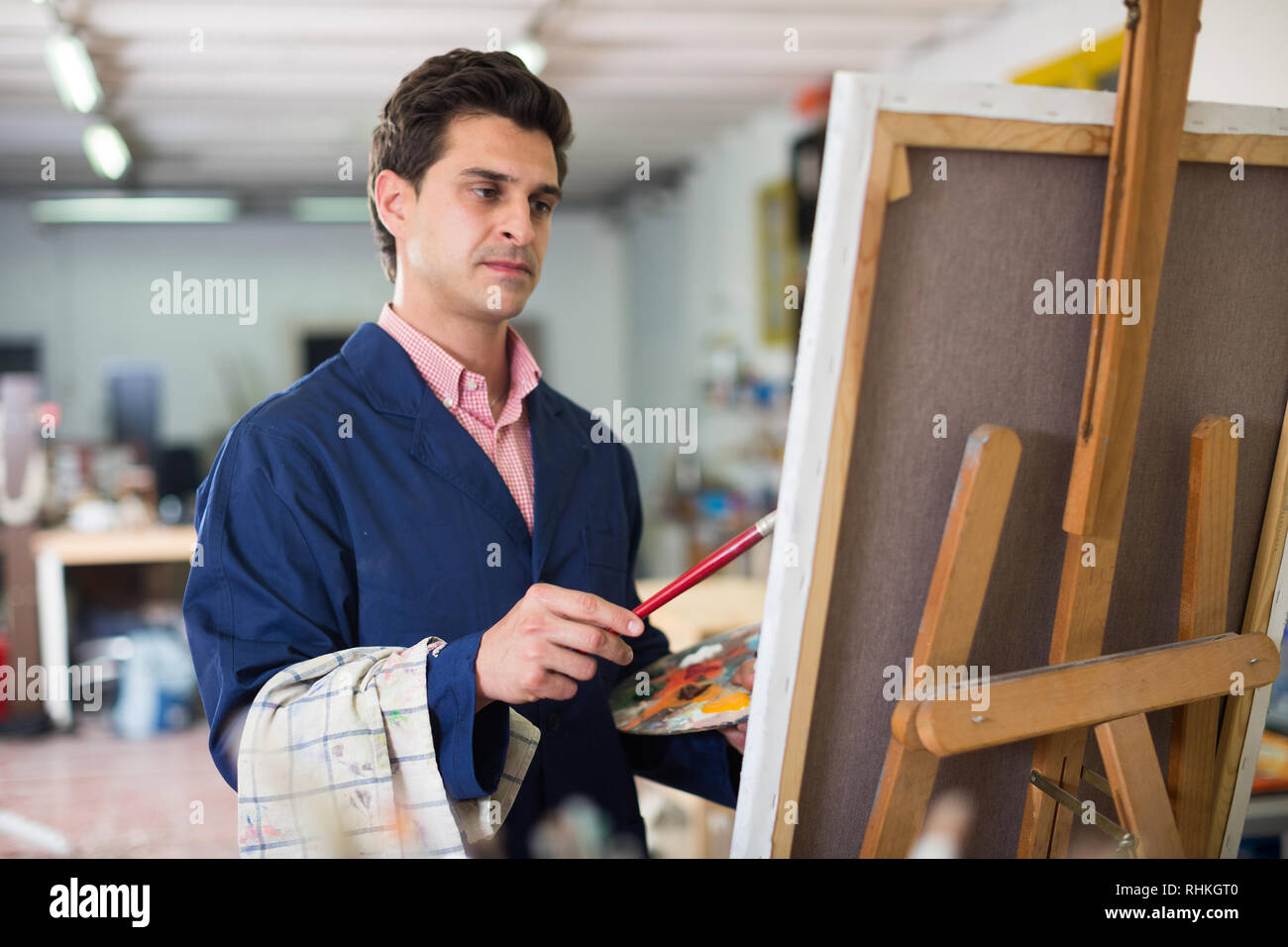 Happy art painter holding artist palette and painting on canvas Stock ...