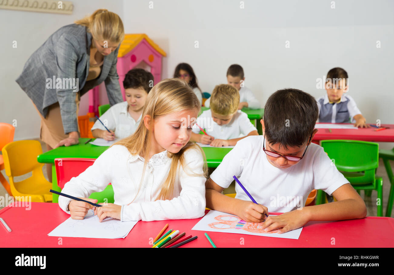 Portrait of schoolchildren sitting in classroom and chatting during ...
