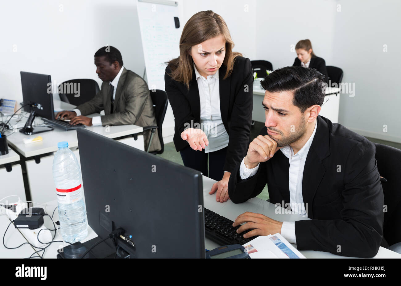 Unhappy man manager working at laptop and angry female boss pointinting ...