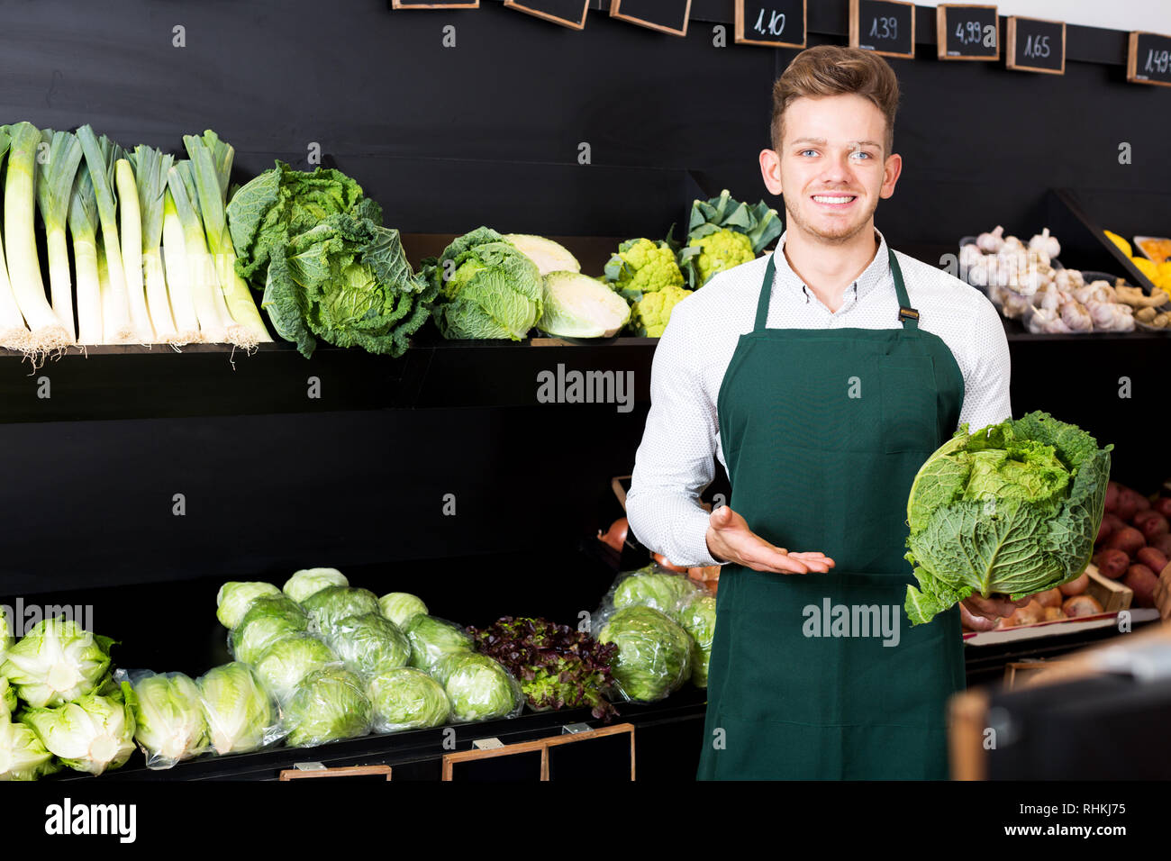 Male shop assistant demonstrating cabbage in grocery shop Stock Photo ...