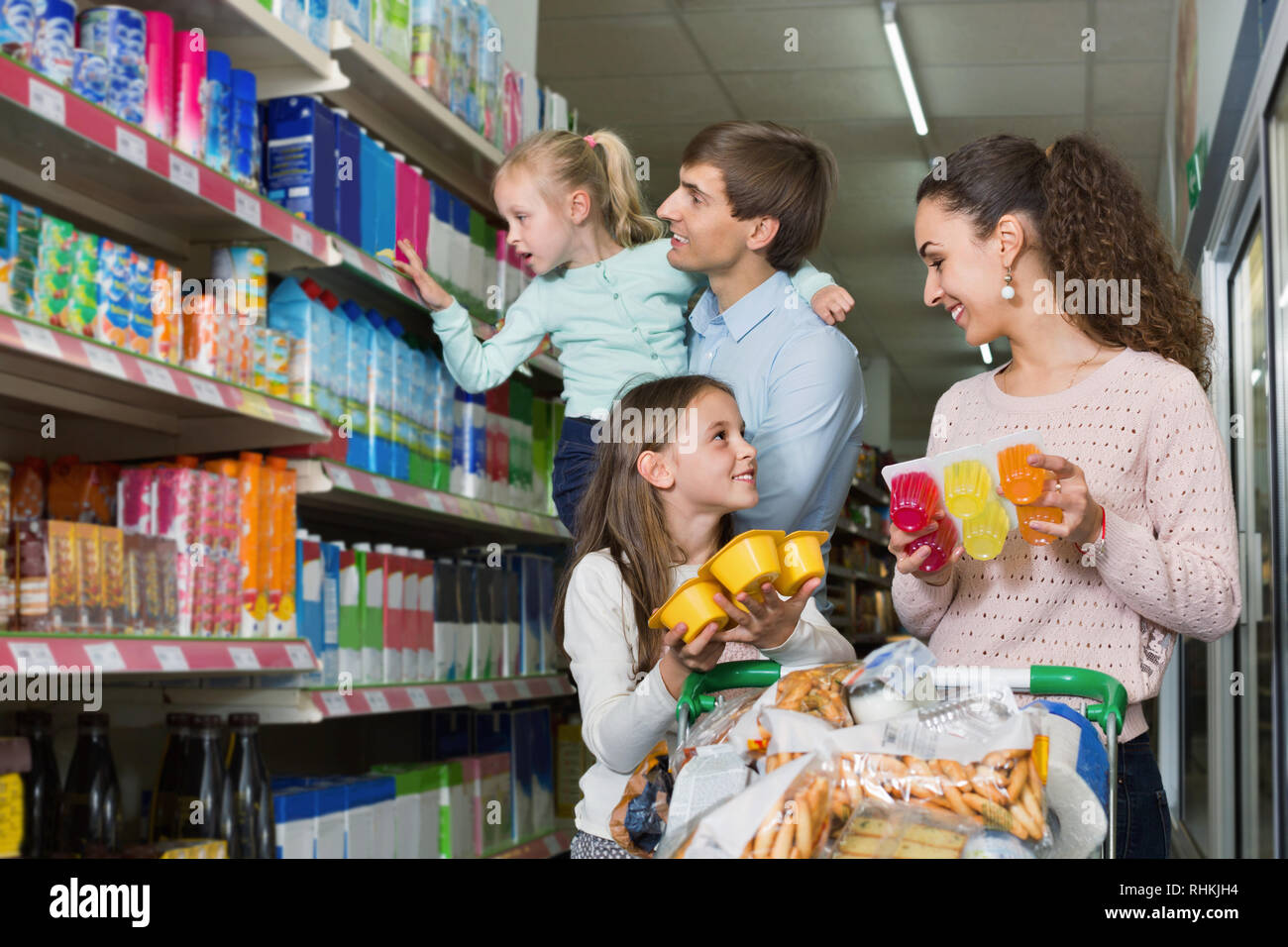 Cheerful smiling family with two daughters purchasing yoghurts in ...