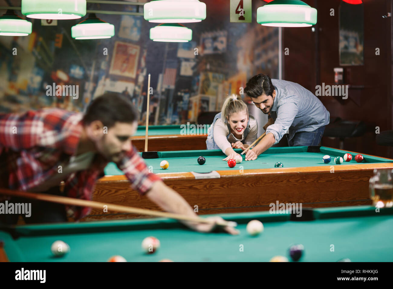 Happy young people enjoying playing pool together Stock Photo - Alamy