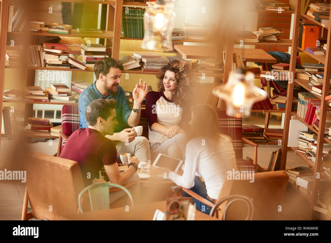 Two young men and women in conversation in library Stock Photo - Alamy