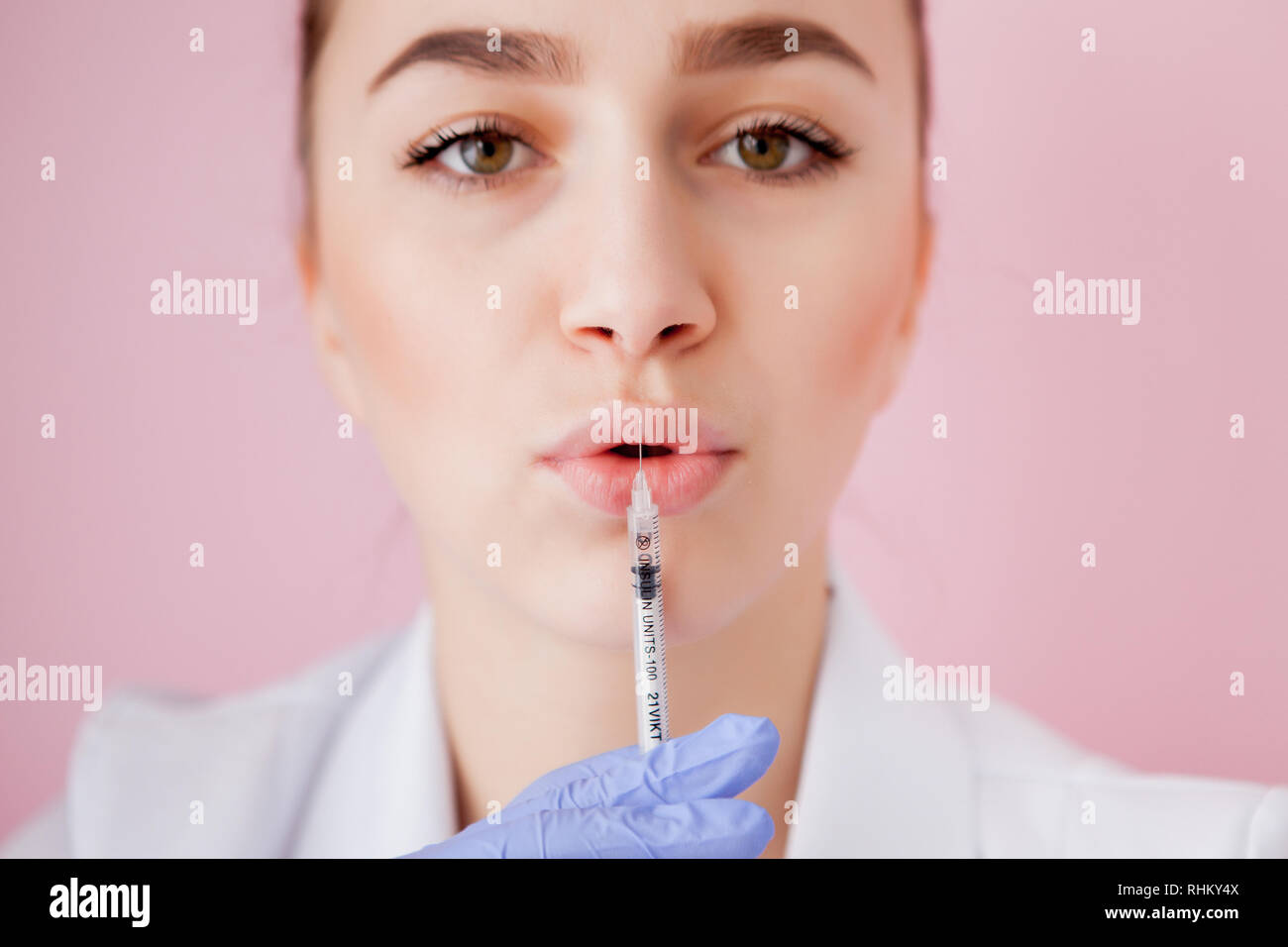 Close up nurse holding a syringe for injection, on pink background ...
